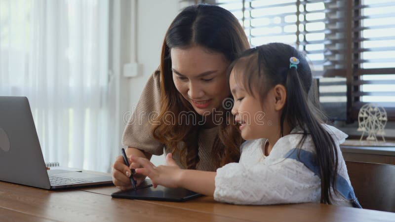 Mother Working with Laptop Computer at Home and Help Daughter Doing ...
