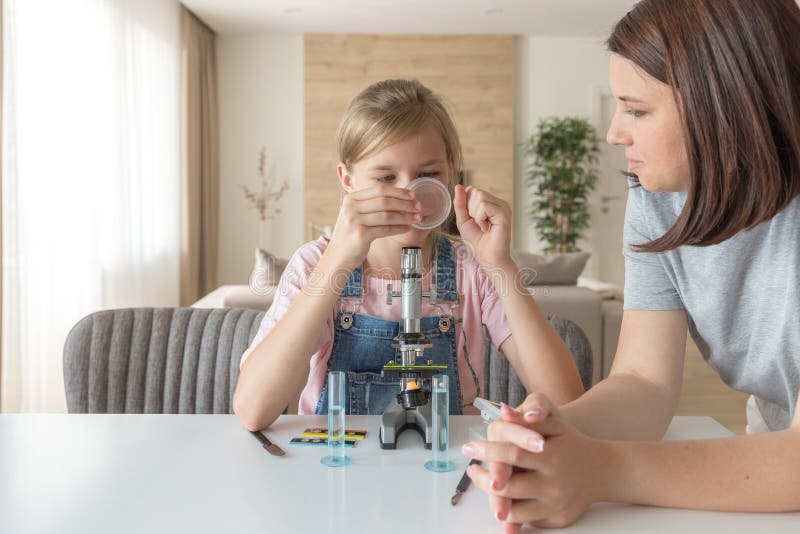 Mother and Young Daughter Doing Some Experiments with Microscope at ...