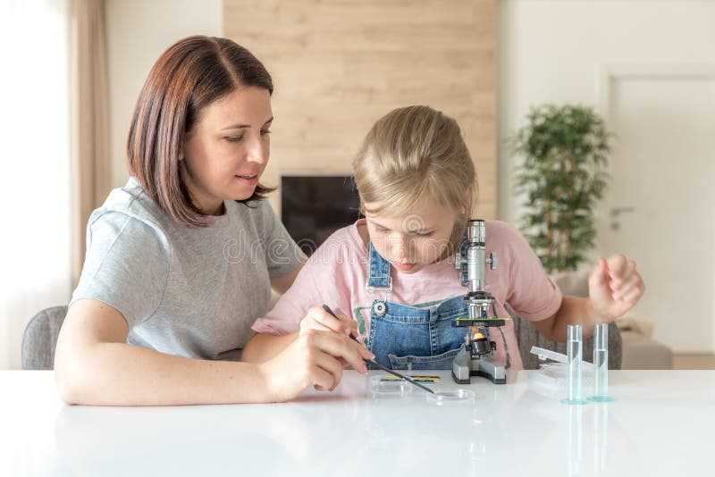 Mother and Young Daughter Doing Some Experiments with Microscope at ...