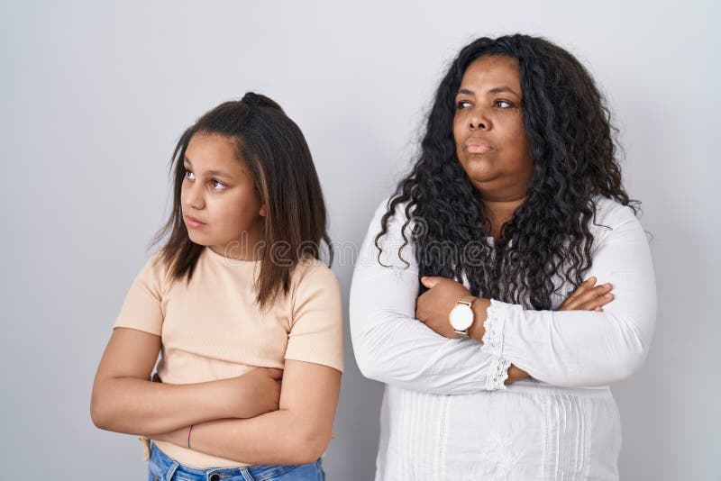 Mother And Young Daughter Standing Over White Background Looking To The