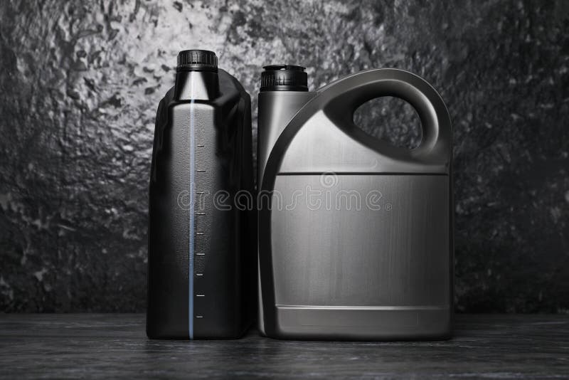 Motor Oil in Different Canisters on Black Table Near Dark Wall Stock ...