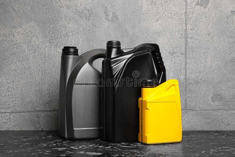 Motor Oil in Different Canisters on Black Table Near Grey Wall Stock ...