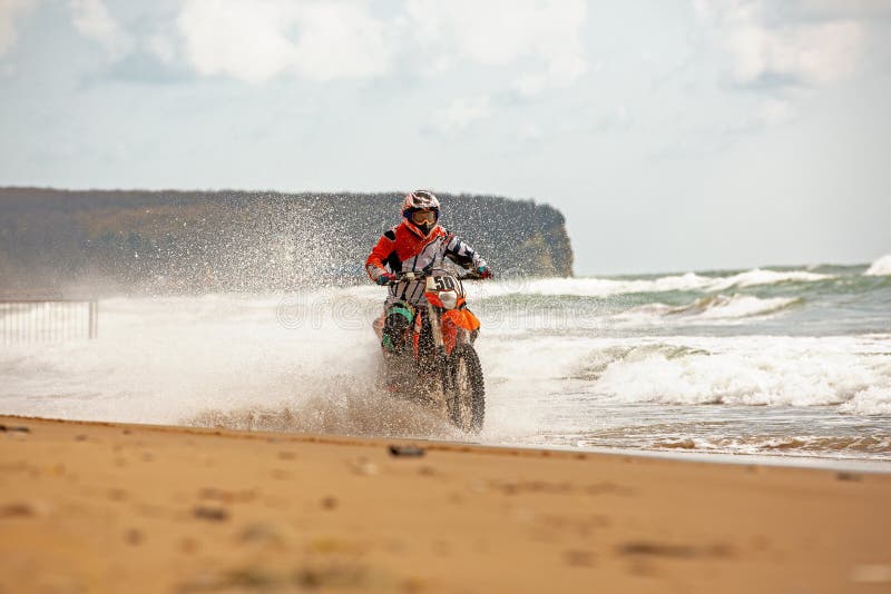 Motorcyclist in a Protective Suit Rides a Motorcycle on the Sea ...