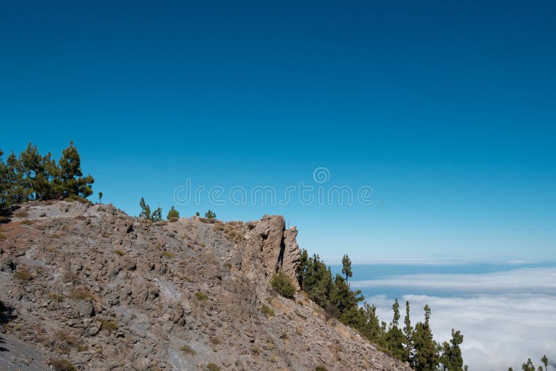 Mountain Cliff Above Clouds with Clear Blue Sky Background - Stock ...