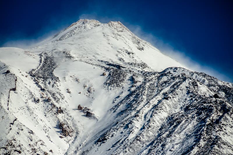 A Mountain Covered in Snow with a Cloud of Smoke Coming from the Top ...