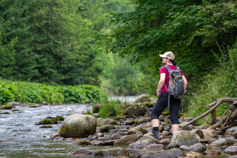 On a Mountain Hike, a Woman Stops by a Stream and Looks Around Stock ...
