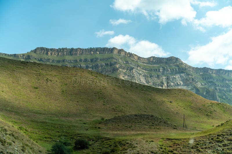 A Mountain Range with a Green Hillside. the Sky is Clear and Blue. the ...