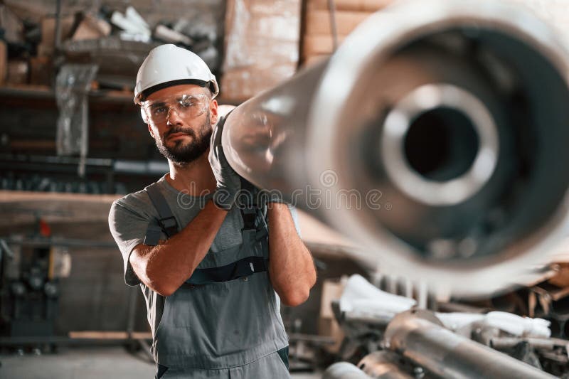 Moving Big Metal Pipe. Young Factory Worker in Grey Uniform Stock Image ...