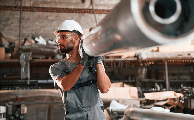Moving Big Metal Pipe. Young Factory Worker in Grey Uniform Stock Image ...