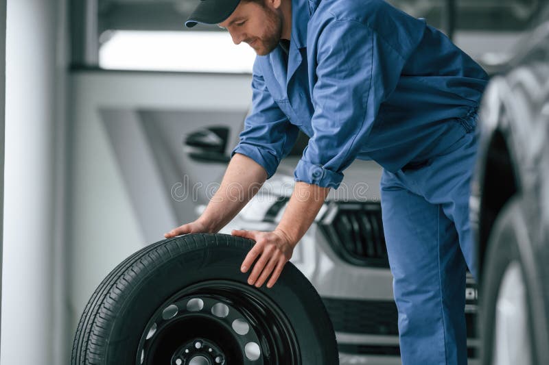 Moving the Tire. Man in Blue Uniform is Working in the Car Service ...
