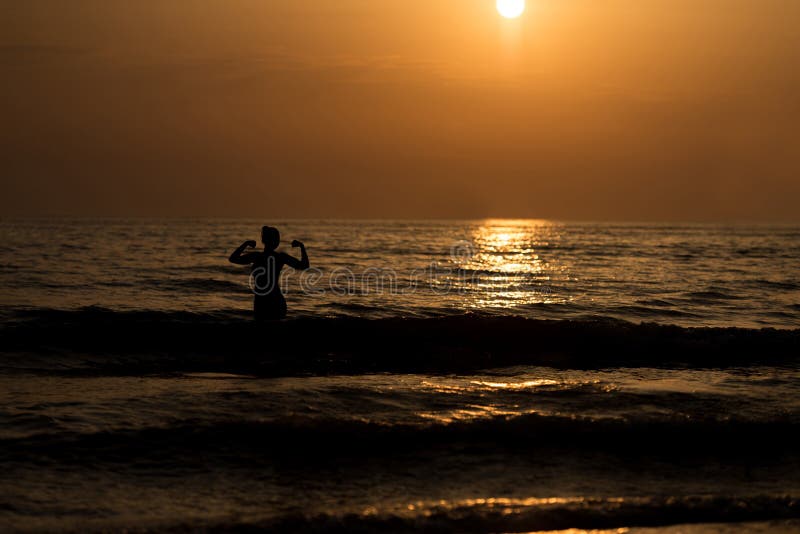 Muchacha Que Dobla Los Músculos En La Silueta De La Playa Foto de ... Muchacha Que Dobla Los Músculos En La Silueta De La Playa Foto de ...