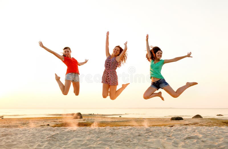 Muchachas Adolescentes Sonrientes Que Saltan En La Playa Imagen De