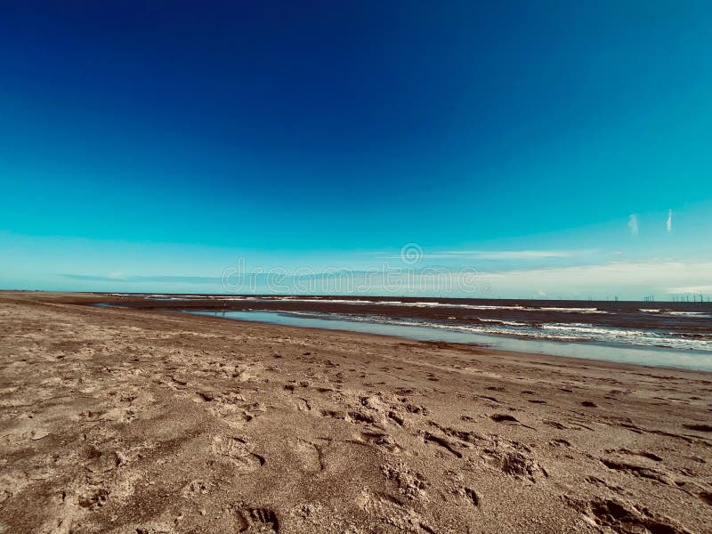 Muddy Beach with Footsteps Under a Blue Sky Stock Photo - Image of sand ...