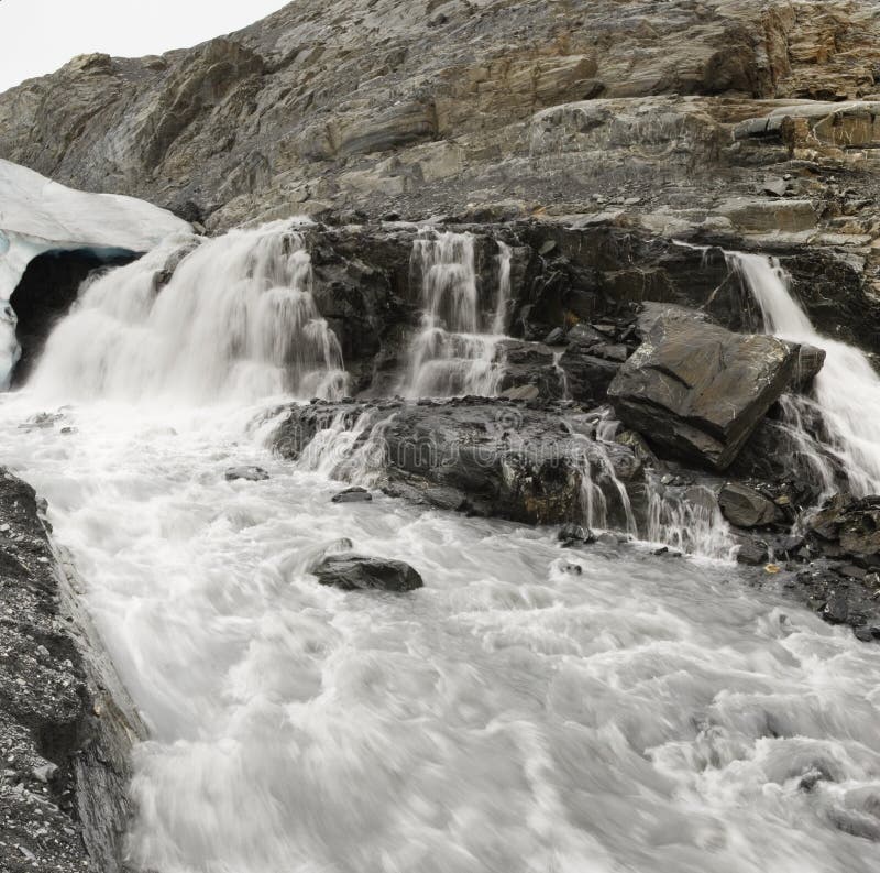 Muddy River with Waterfall Flowing from Below the Glacier Stock Photo ...