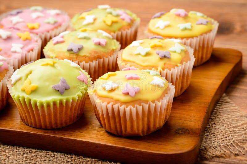 Muffins Covered with Colorful Icing Shugar on the Wooden Board. Stock ...