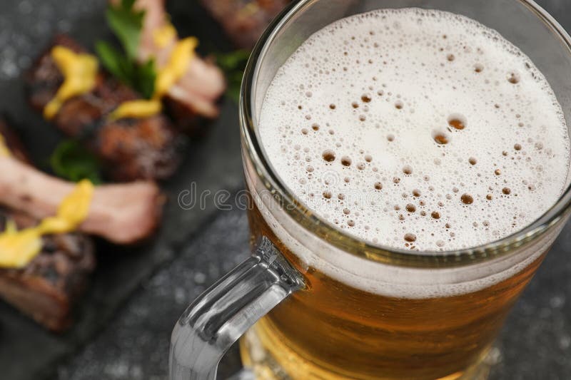 Mug with Beer and Delicious Grilled Ribs on Table, Closeup. Space for ...