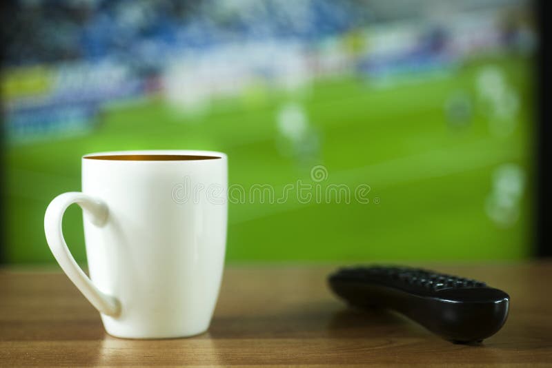 Mug with Coffee and TV Remote Control on the Background of the TV ...