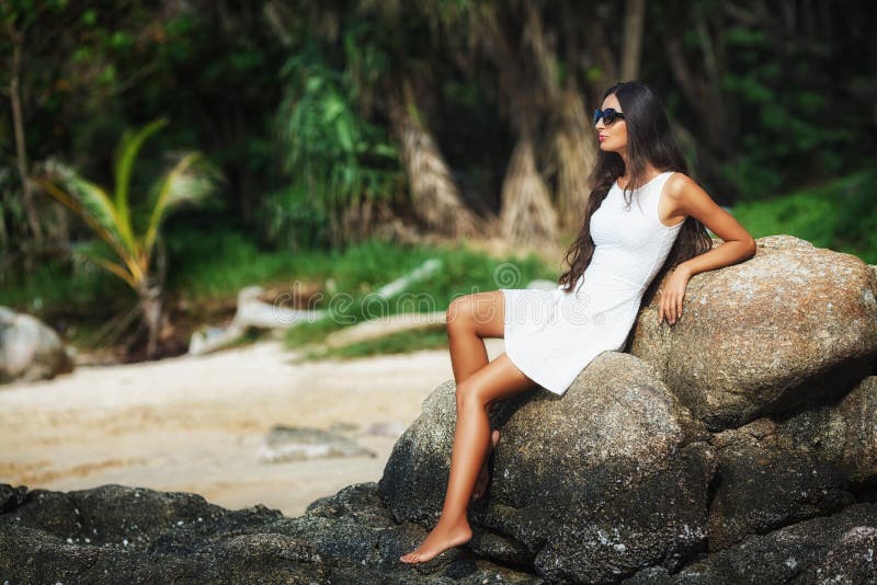 Mujer Bronceada Hermosa Que Se Sienta En Piedra Foto de archivo ...