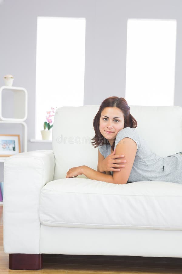 Mujer Tranquila Atractiva Que Miente En Un Sofá Blanco Imagen de ...