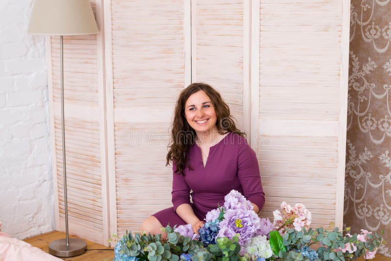 Mulher Bonita Que Guarda Flores E Olhares in Camera Imagem de Stock ...