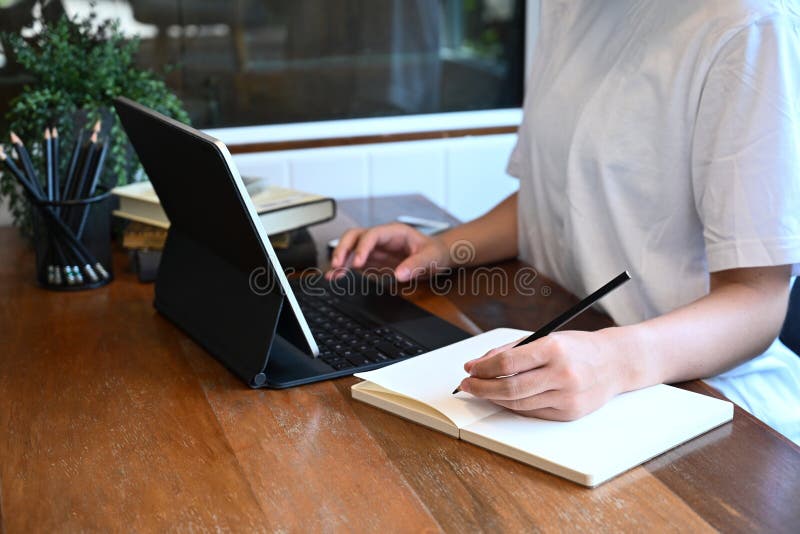 Mulher Criativa Trabalhando Com Tablet E Anotando No Notebook. Foto de ...