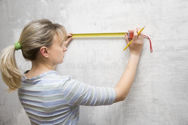 Mulher Do Trabalhador Que Mede Na Parede Foto de Stock - Imagem de ...