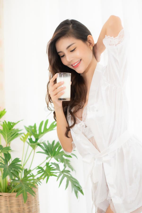 Linda Mulher Vestindo Um Vestido Branco Segurando Um Copo De Leite ... Linda Mulher Vestindo Um Vestido Branco Segurando Um Copo De Leite ...