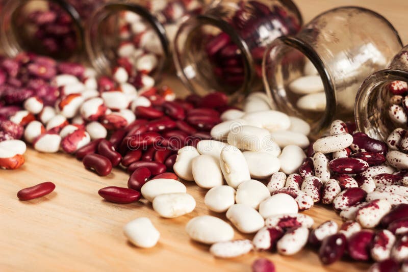 Multi-colored Beans are Poured Out of Jars on the Table. White, Red and ...