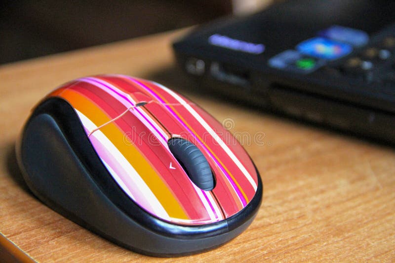 A Multi-colored Computer Mouse Lies on the Table Next To a Laptop Stock ...