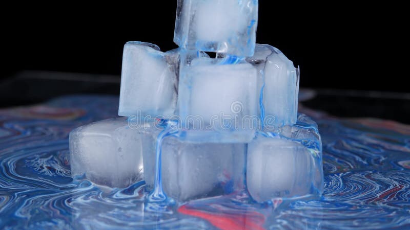 Multi-colored Paint Spreads Over the Surface of the Ice Cubes and Flows ...