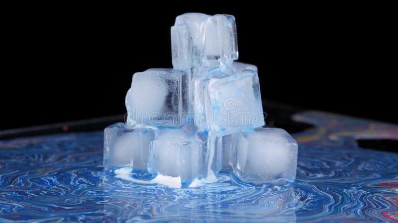 Multi-colored Paint Spreads Over the Surface of the Ice Cubes and Flows ...