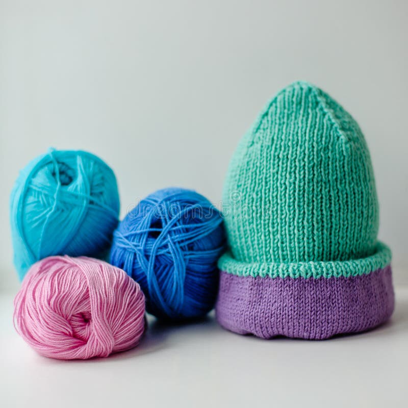 Multi-colored Skeins of Woolen Yarn and a Knitted Hat on a Light ...