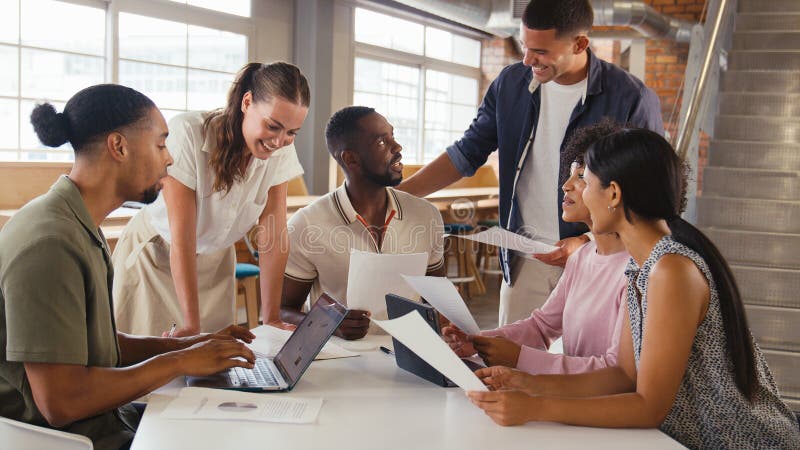 Multi-Cultural Business Team Meeting Around Desk in Modern Open Plan ...