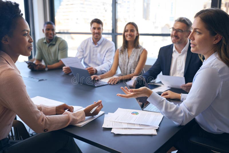 Multi-Cultural Business Team Meeting Around Office Boardroom Table with ...