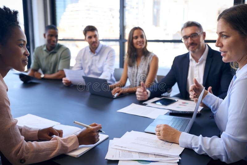 Multi-Cultural Business Team Meeting Around Office Boardroom Table with ...