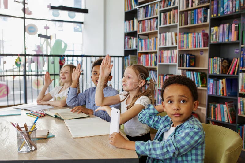 Multi-ethnic Pupils Study and Write at Table in Library or Classroom ...