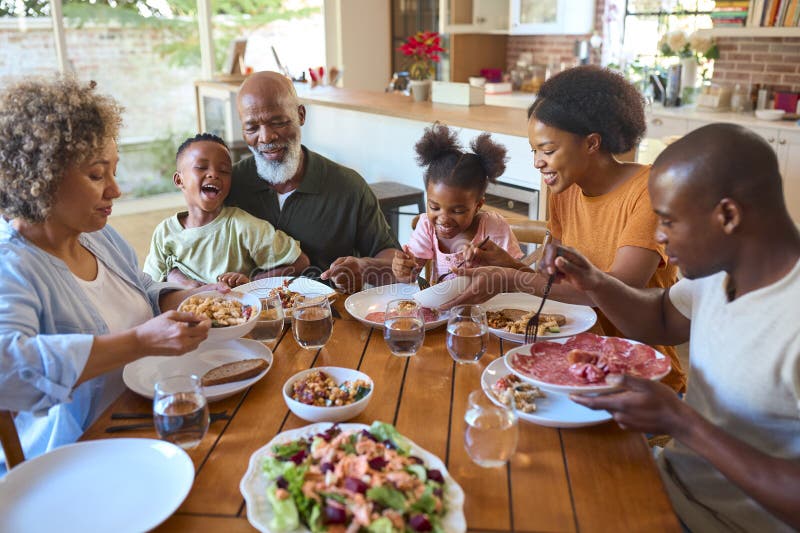 Multi-Generation Family Around Table Serving and Eating Meal at Home ...