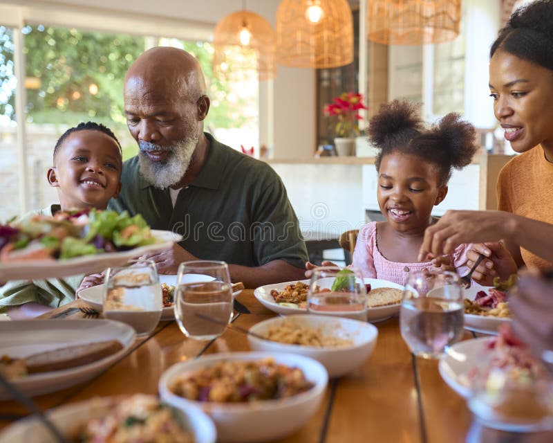 Multi-Generation Family Around Table Serving and Eating Meal at Home ...