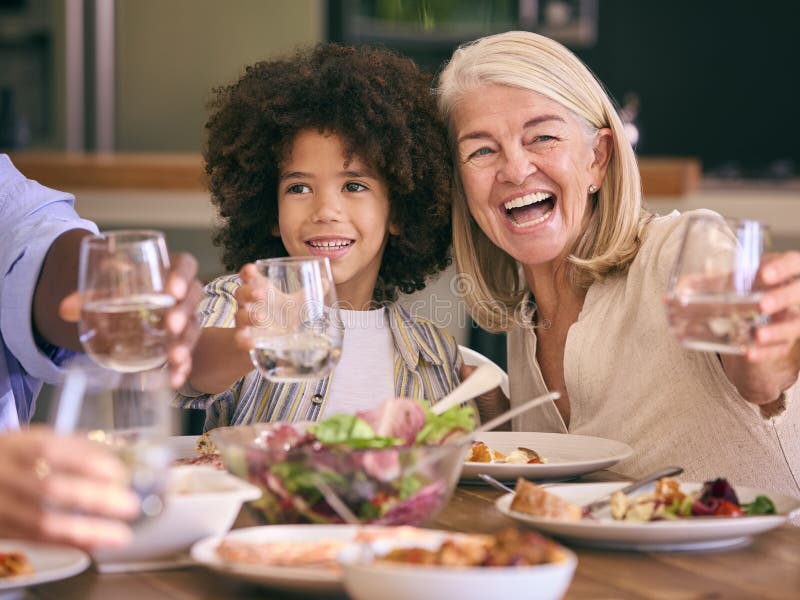 Multi-Generation Family Doing Cheers with Water As they Sit Around ...