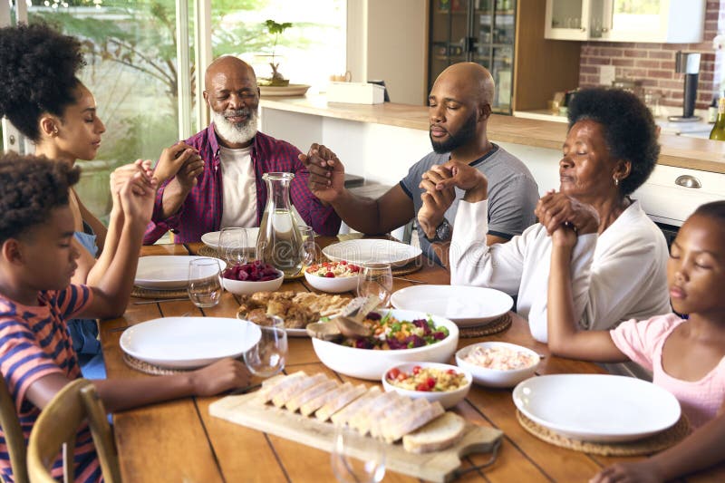 Multi-Generation Family Joining Hands and Saying Prayer before Meal at ...