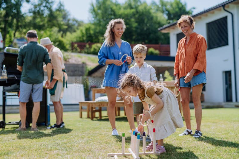 Multi Generation Family Playing Throw a Ring Game when Grilling Outside ...