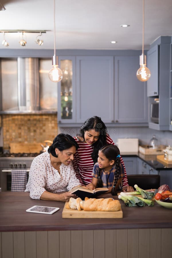 Multi-generation Family Reading Book Together in Kitchen Stock Photo ...