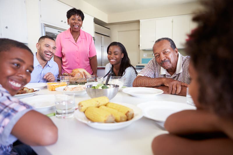 Multi-Generation Family Sitting Around Table Eating Meal Stock Image ...