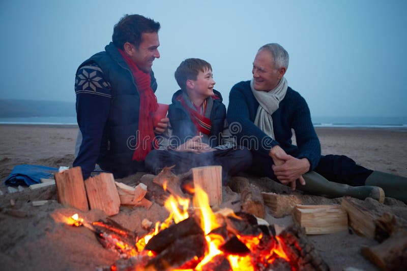 Multi Generation Family Sitting by Fire on Winter Beach Stock Photo ...