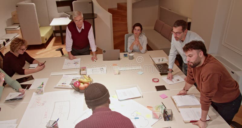 A Multi-generational Team Collaborates at a Conference Table ...