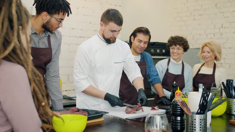 Multi-racial Group of People Watching Chef Cutting Meat during Cooking ...