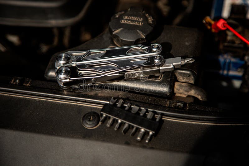 A Multi-tool with Various Attachments is Placed on a Car Engine ...