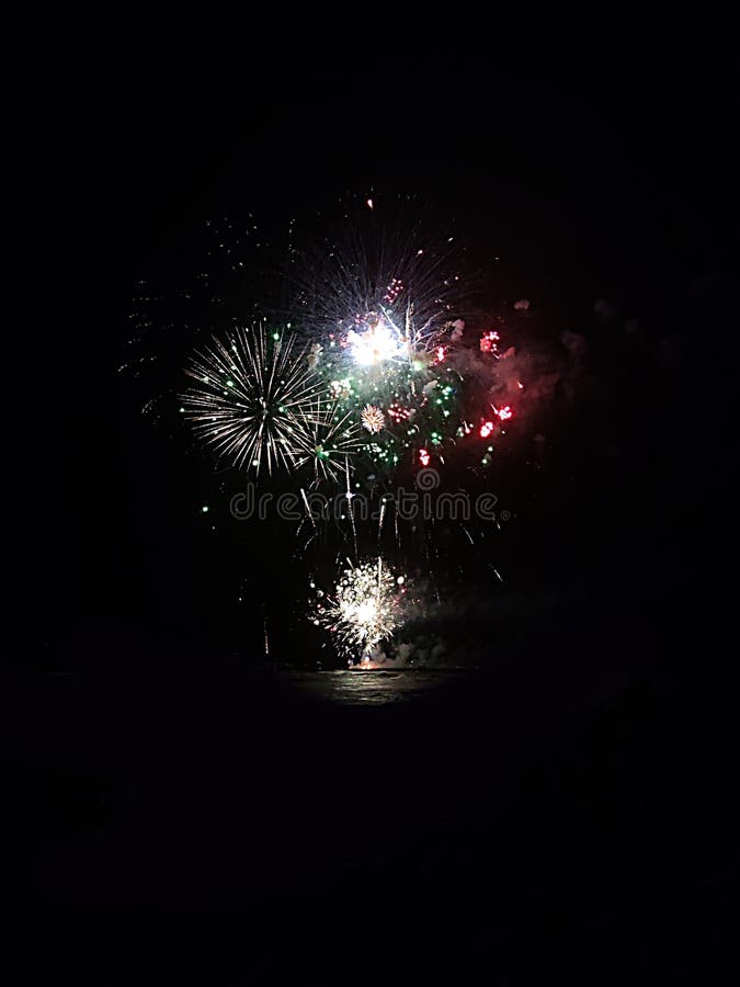 Multicolored Fireworks Over Water in the Black Night Sky Stock Photo ...