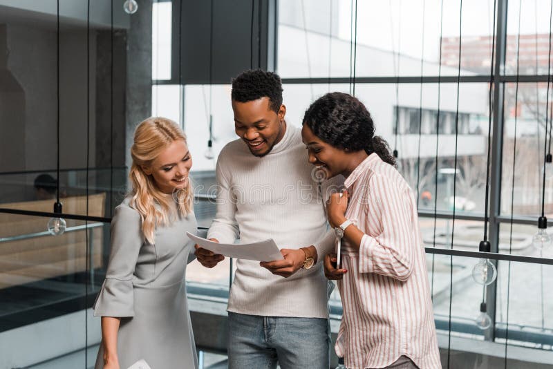 Multicultural Businesspeople Looking at Papers while Stock Photo ...