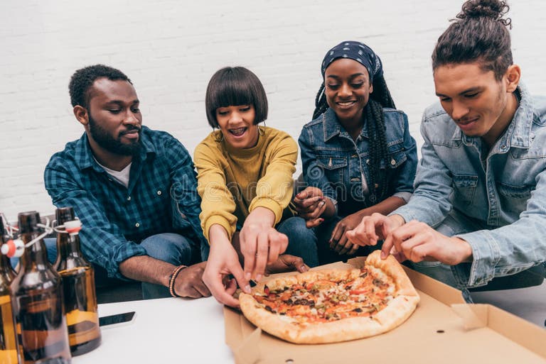 Multicultural Friends Eating Pizza at Table with Bottles of Stock Photo ...